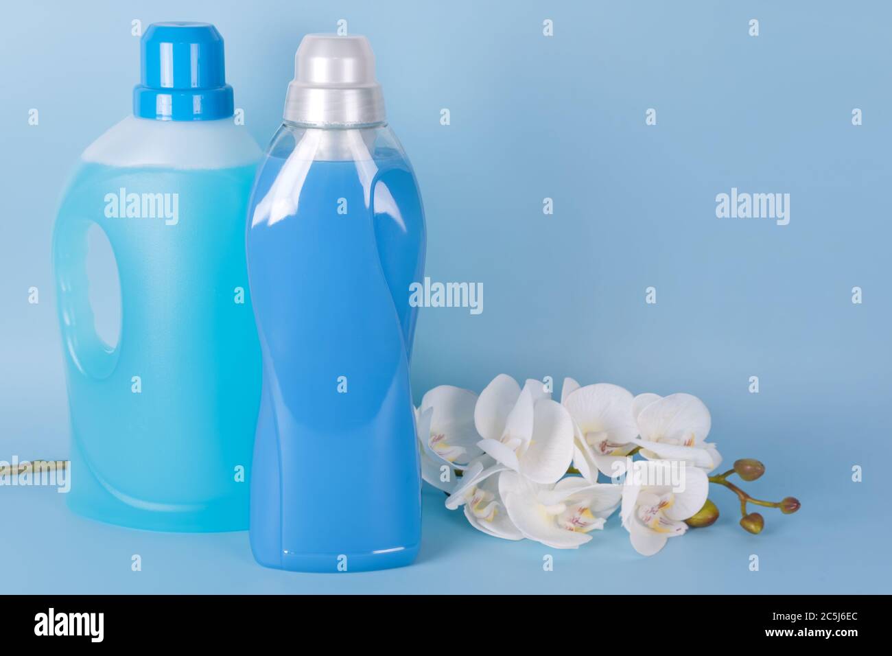 Bottles of detergent and fabric softener with orchid flowers on blue ...
