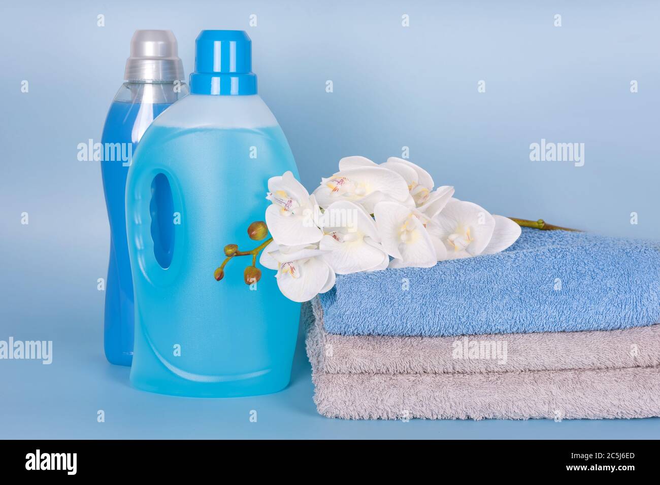 Bottles of detergent and fabric softener with clean towels and orchid ...