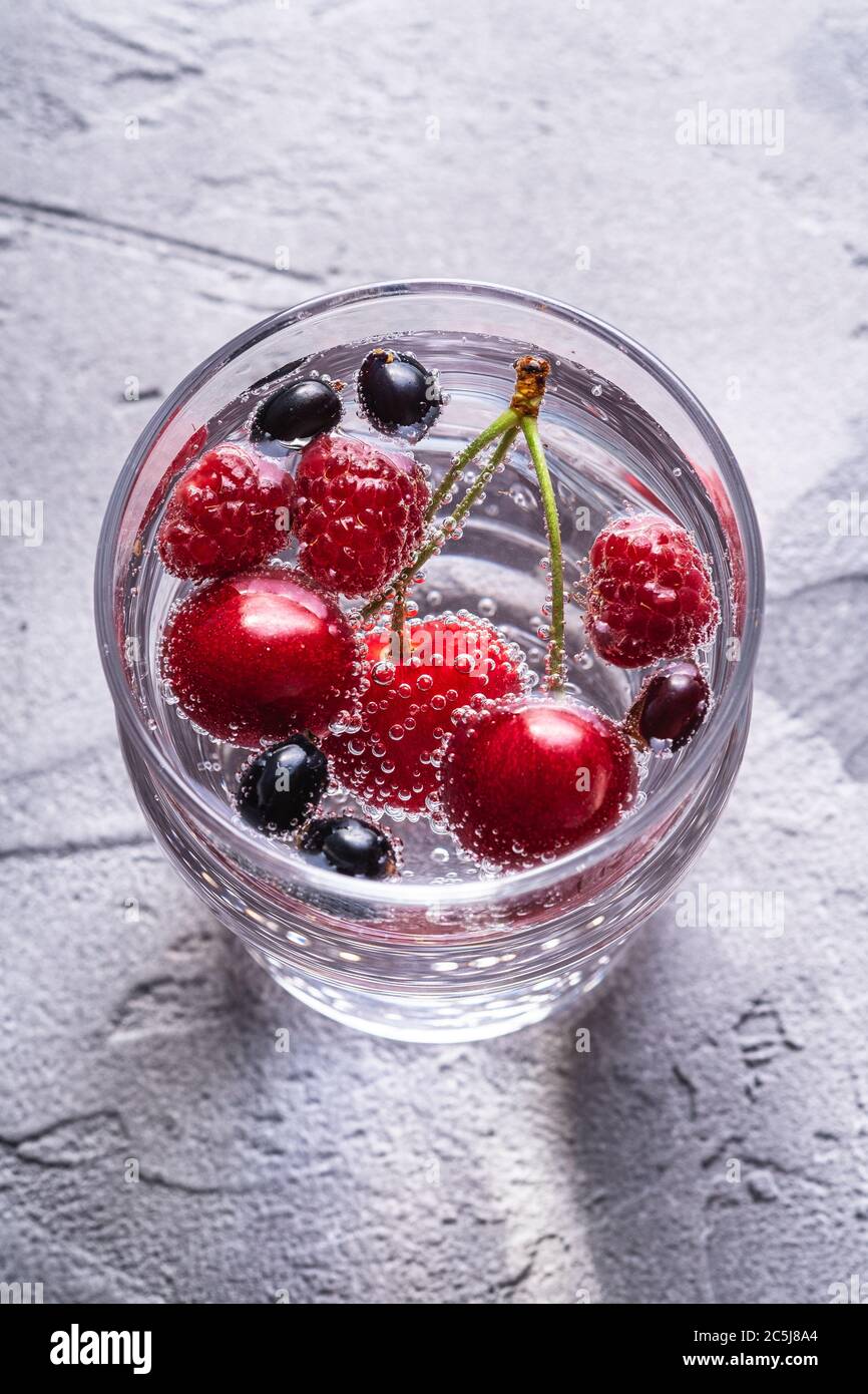 Fresh cold sparkling water drink with cherry, raspberry and currant ...