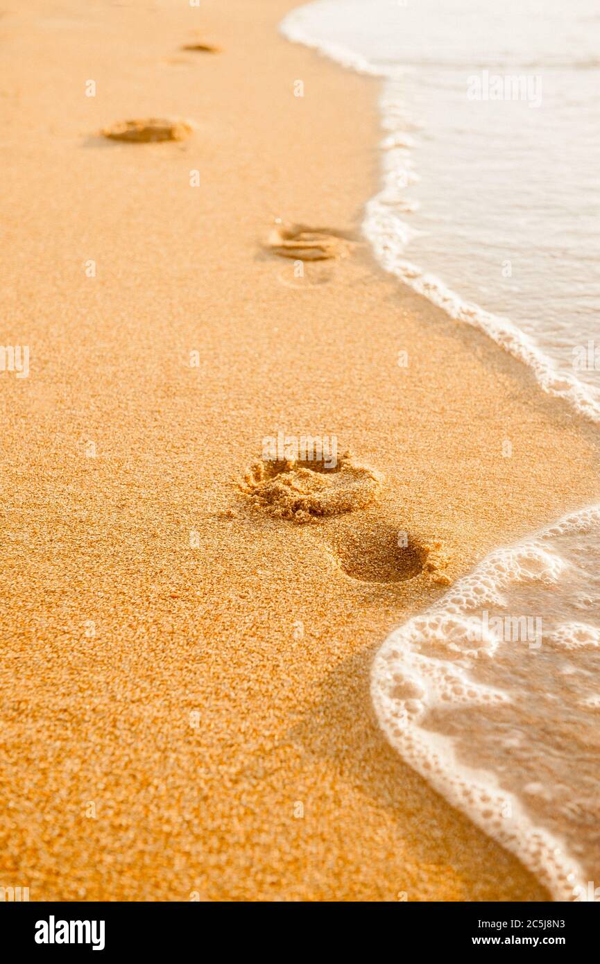Footprints in the sand at sunset. beach with sea waves. Footsteps on ...