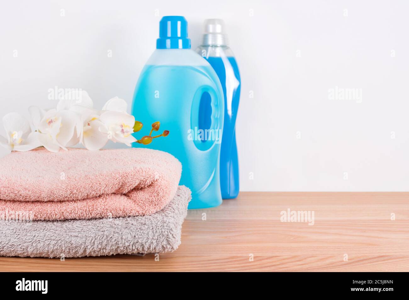 Bottles of detergent and fabric softener with clean towels and orchid ...
