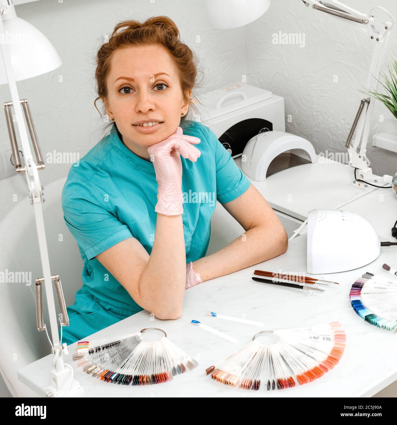 Manicurist at work in the office. Drawing gel polish on tips, creating ...