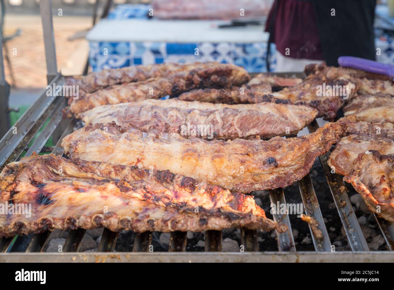 BBQ rack of pork ribs lined up on a large outdoor grill with smoke ...