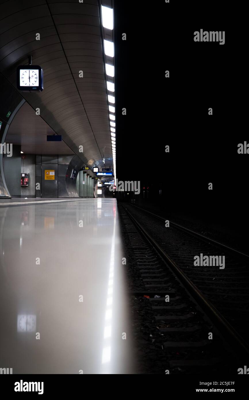 A well lit train station in the underground seperated by a leading line ...