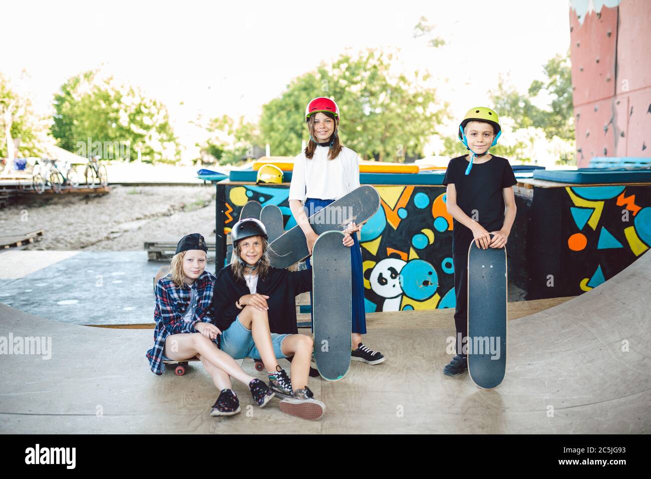 Group of friends athletes skateboarders posing together in a skate park ...