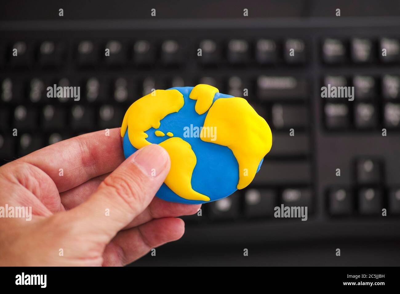 Man holding the planet Earth in his hand over a black computer keyboard ...
