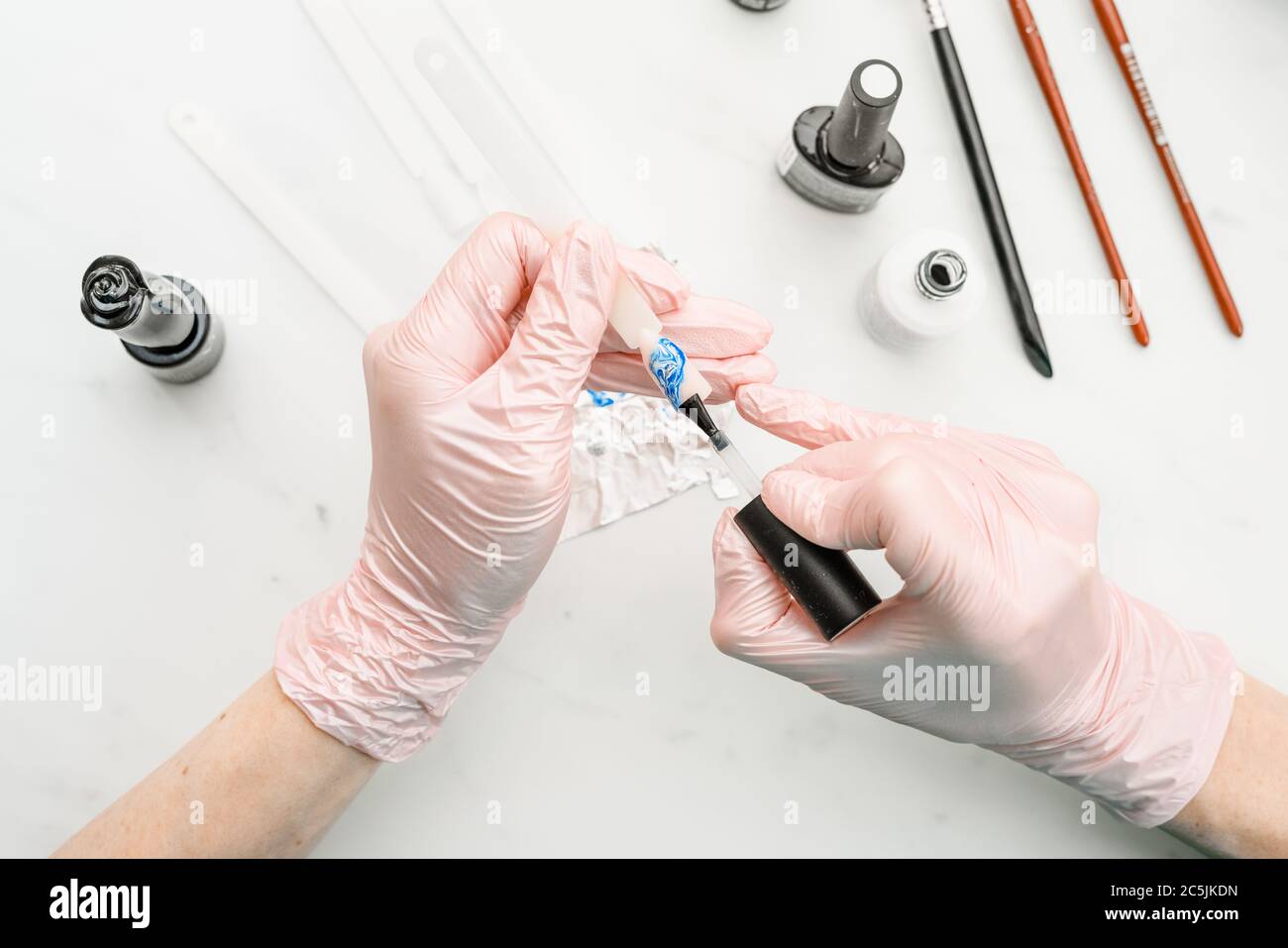 Manicurist at work in the office. Drawing gel polish on tips, creating ...