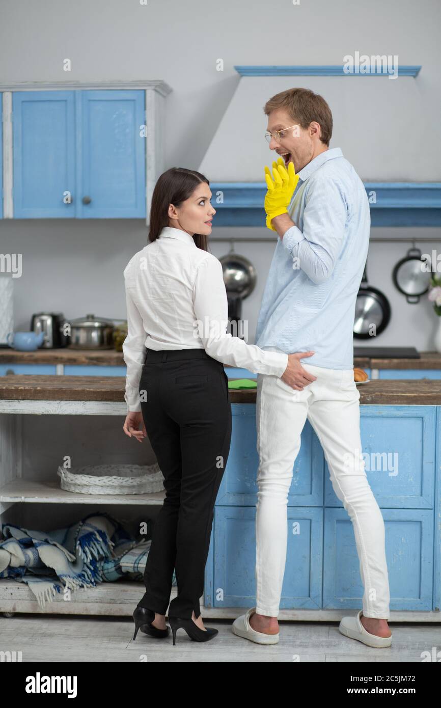 Playful Woman Grabbing Her Husbands Butt In Kitchen Middle Aged Man Dressed In All White And