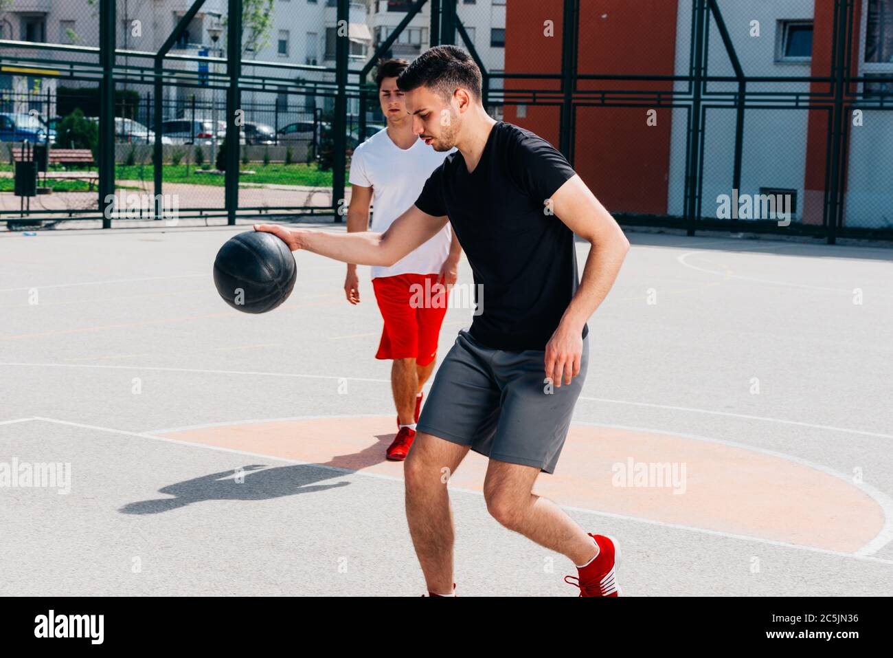 Fit male basketball player early in the morning on a sunny day at the ...