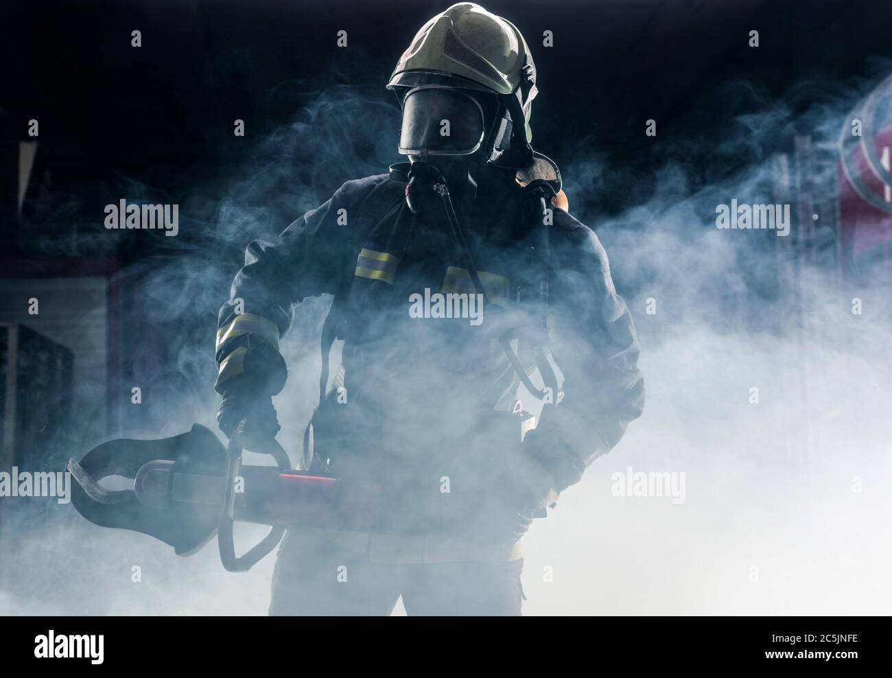 Portrait of a fireman wearing firefighter turnouts and helmet. Dark ...