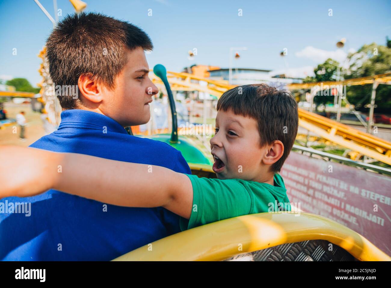 Young people laughing and enjoying a roller coaster ride at the theme ...