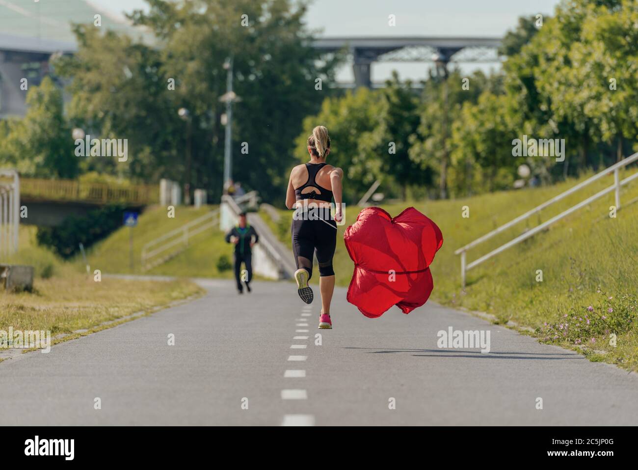 View from the back of a young female athlete running with a parachute ...