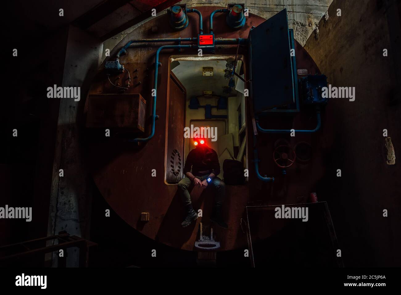 Creepy masked man in gateway corridor of airlock of abandoned bunker ...