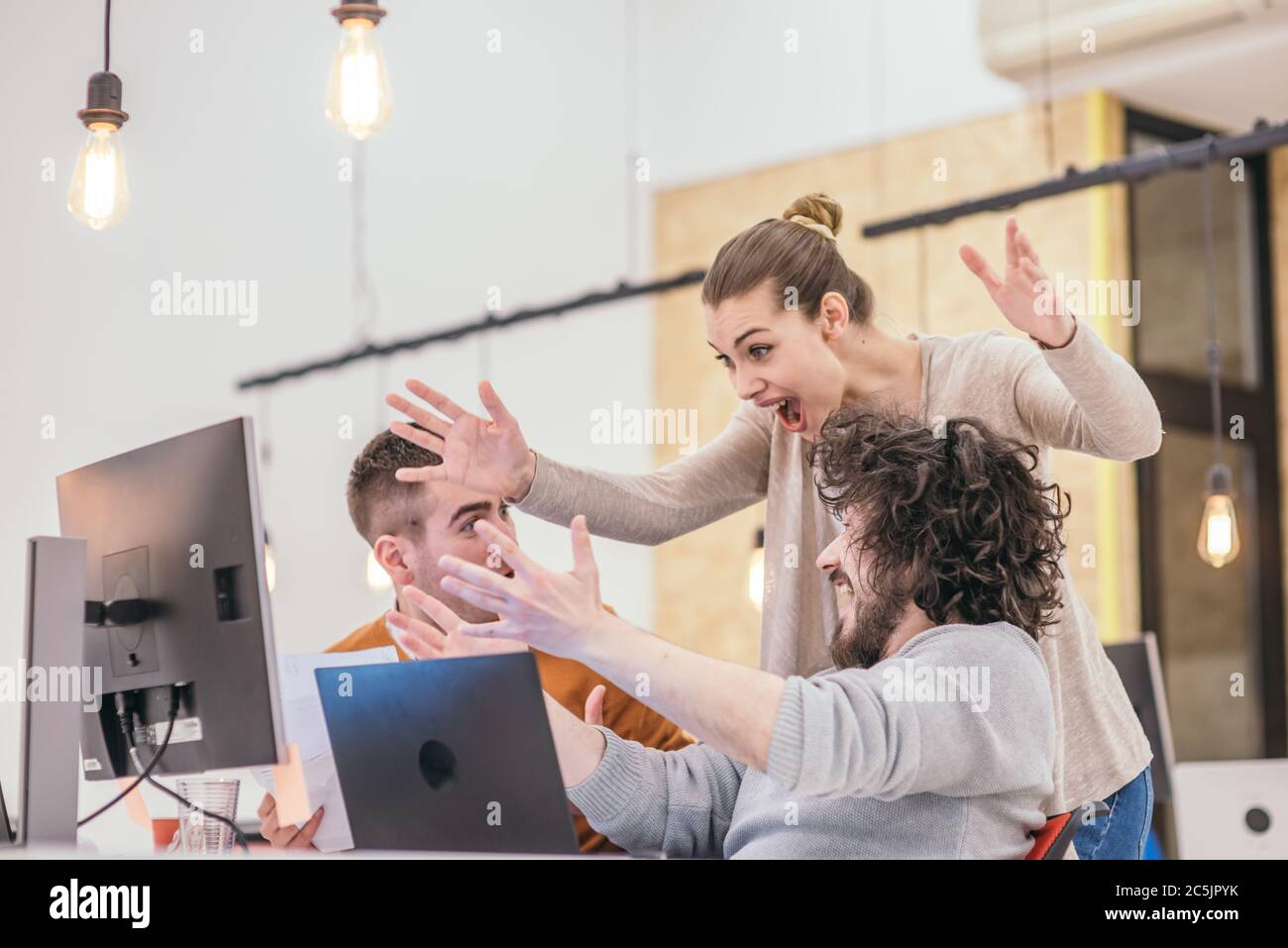 Happy surprise for the teammates. Coworkers cheering while looking at a ...