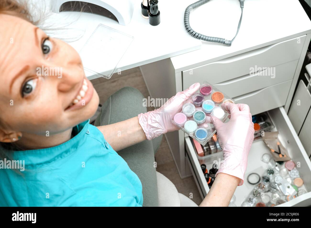 Manicurist at work in the office. Drawing gel polish on tips, creating ...