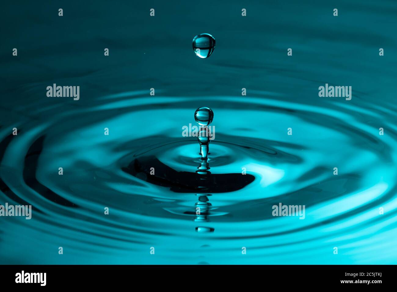 Perfect water drop splashing into smooth water causing ripples Stock ...