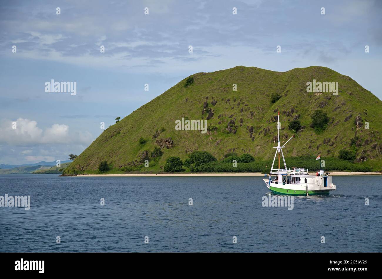 Little lonely boat on the background of a green hill. Lesser Sunda ...