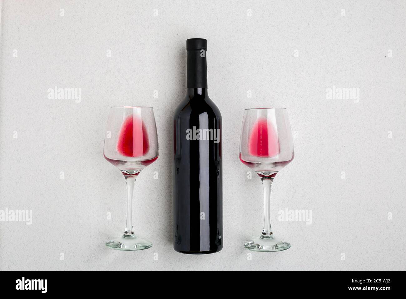 Overhead angled view of a large bottle of red wine, drinking glasses on ...