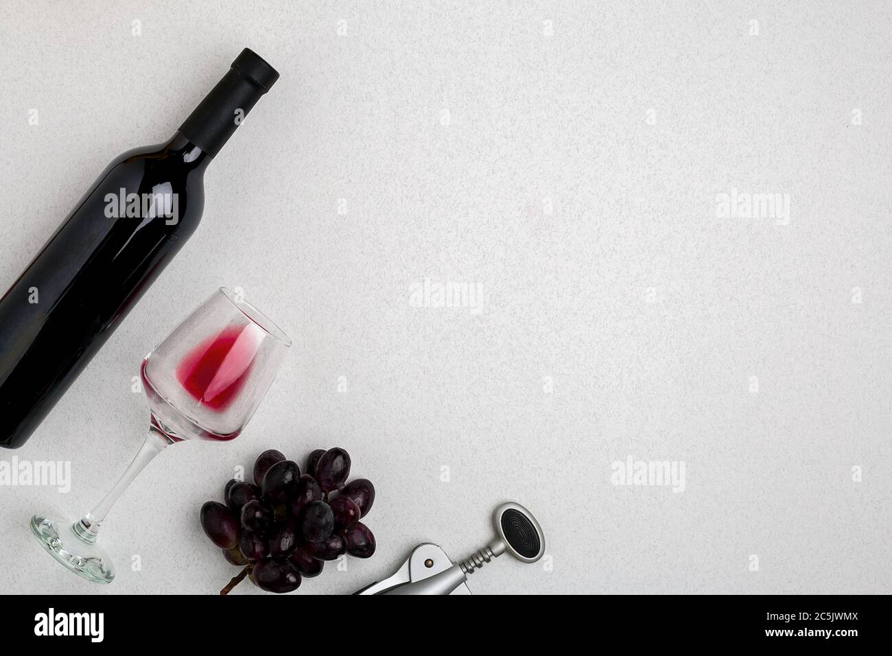 Overhead angled view of a large bottle of red wine, drinking glass on ...