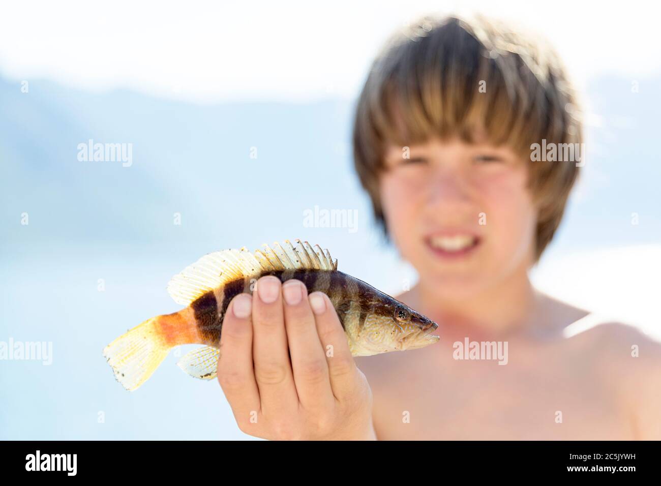 Boy holding a fish that he caught in hand Stock Photo - Alamy