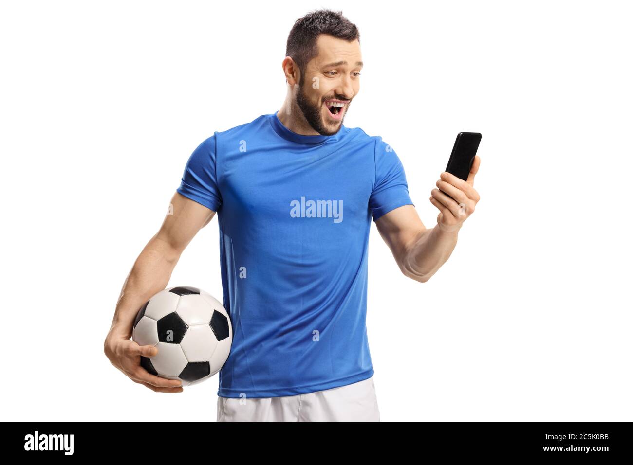 Surprised soccer player holding a ball and looking at a mobile phone ...