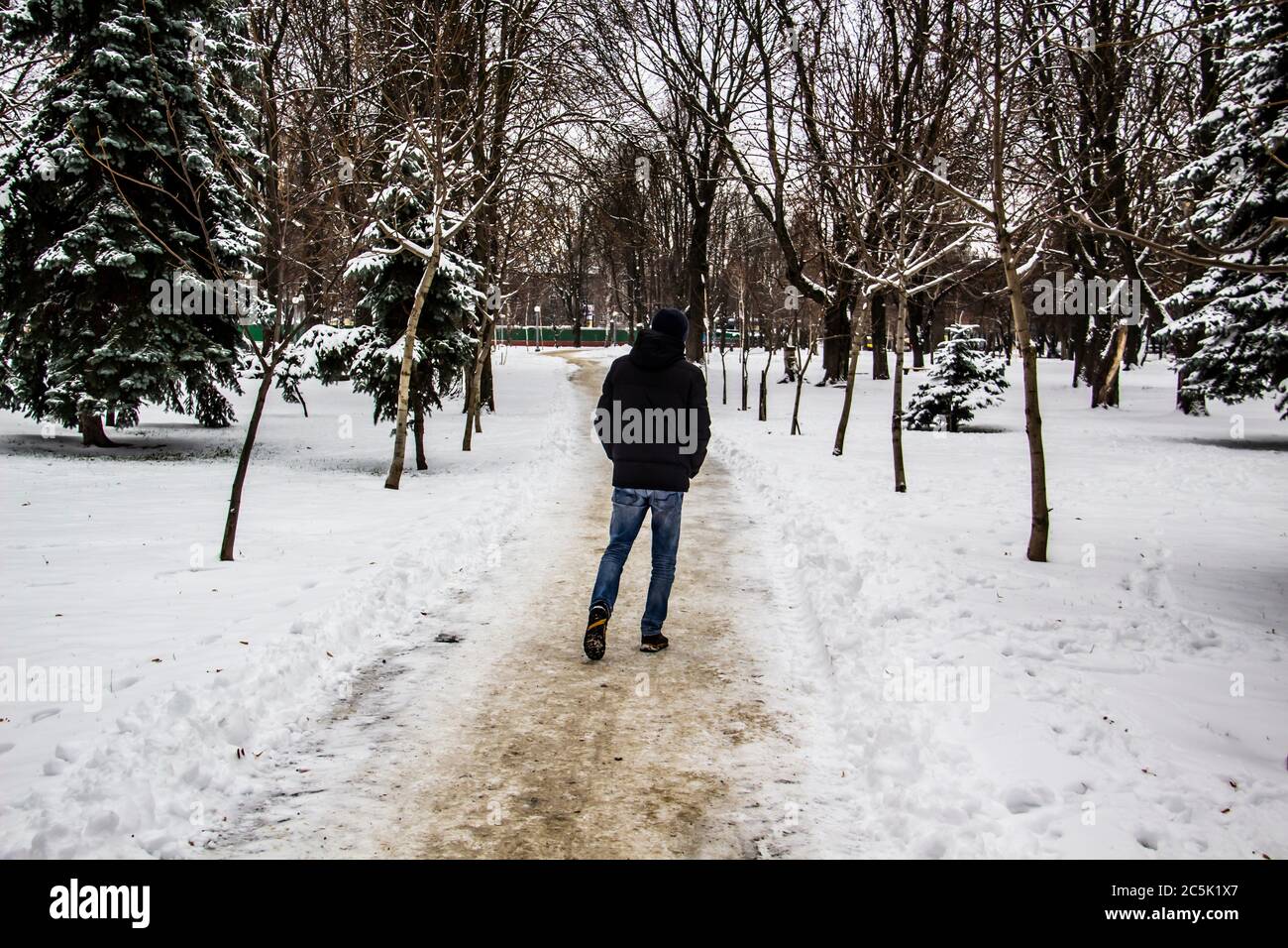 A guy in a black jacket is walking along the road. Silhouette of a man ...