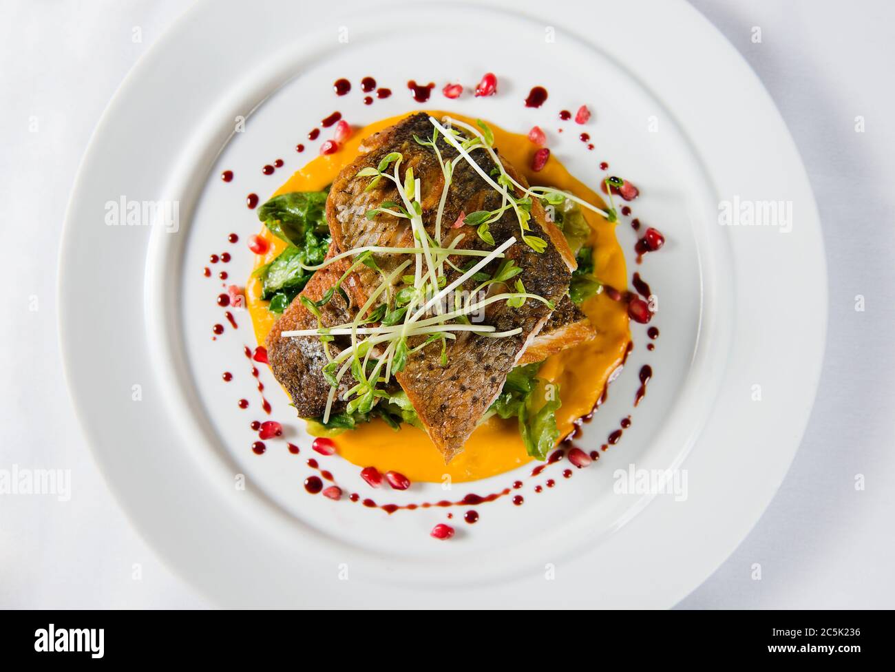 Cooked fish with greens and orange sauce Stock Photo - Alamy