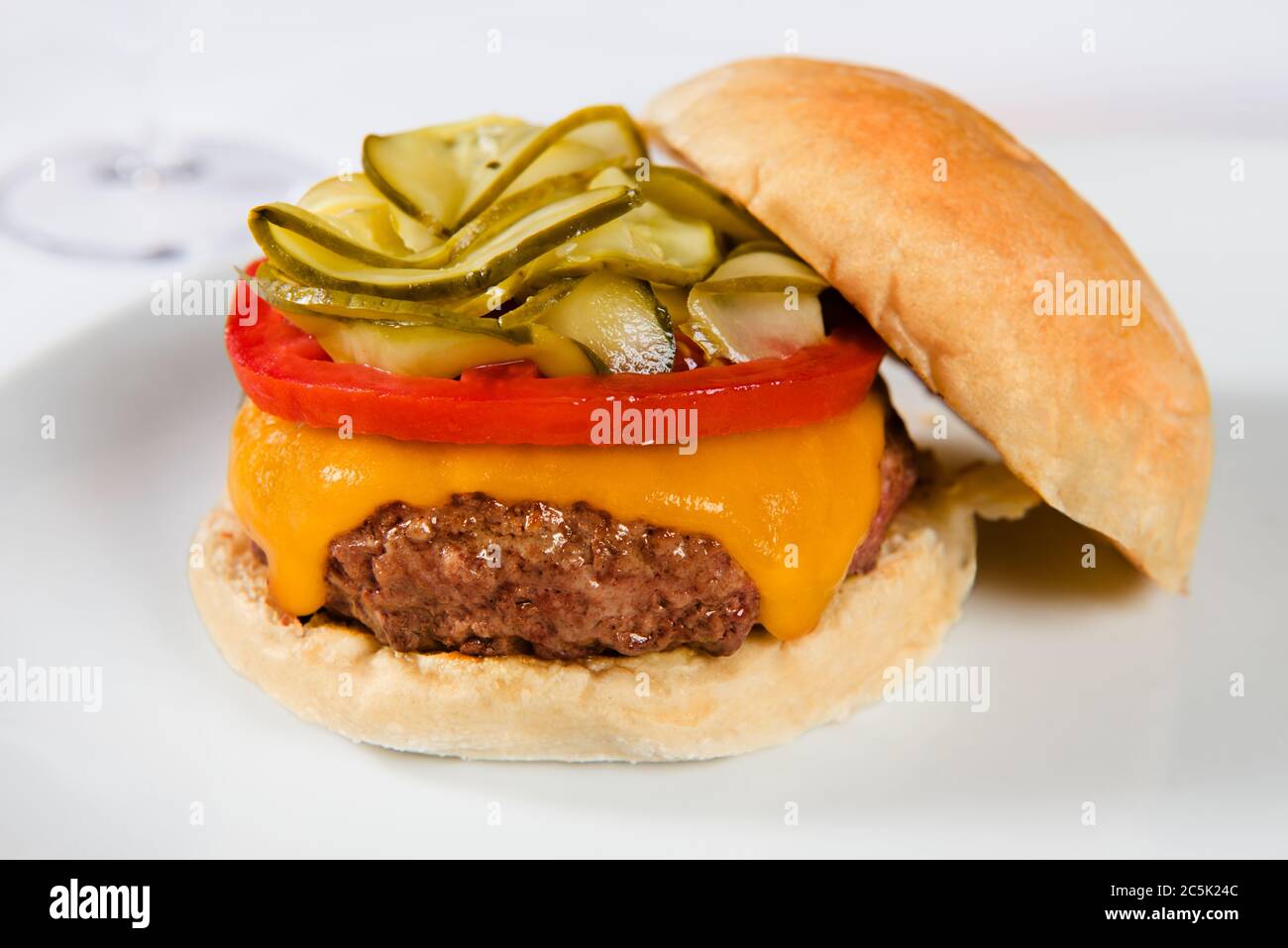 Cheeseburger with cheddar cheese, tomato, and pickles Stock Photo - Alamy