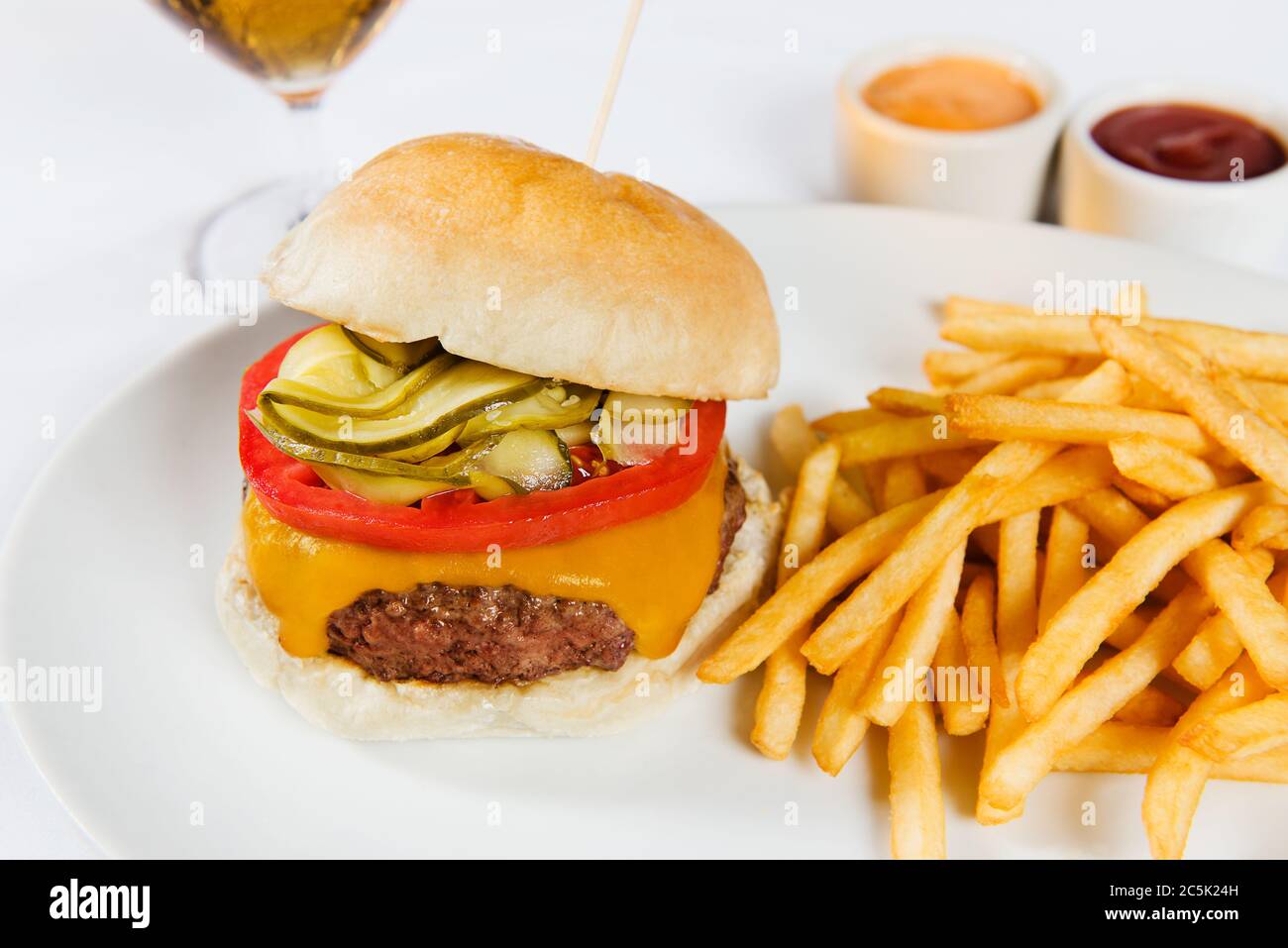 Cheeseburger with cheddar cheese, tomato, pickles and fries Stock Photo ...