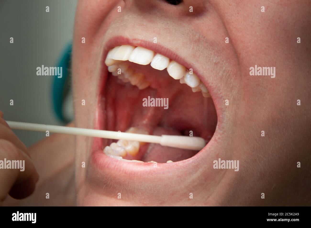Male performing self test using a swab in the throat with the COVID19 ...