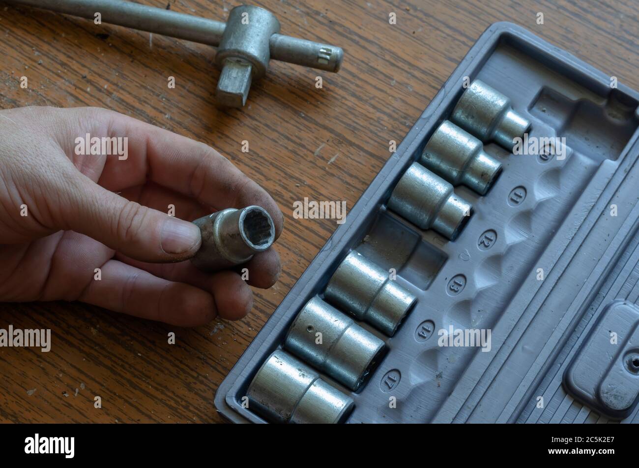Hands of a man choose the size of an allen key. A set of keys in a ...
