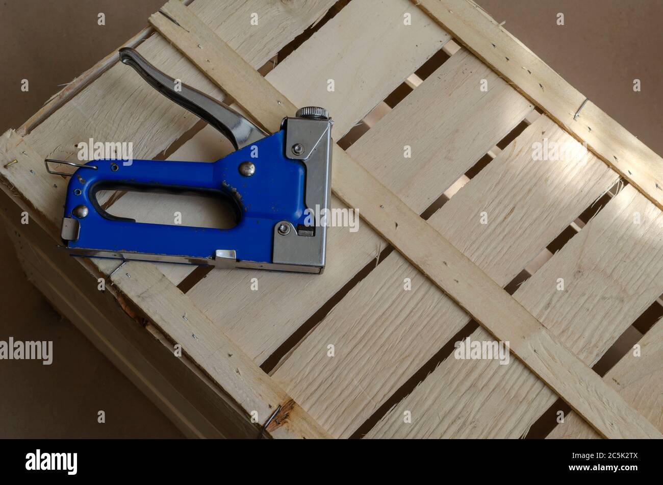 Blue industrial stapler and wooden box in the sunshine indoors ...