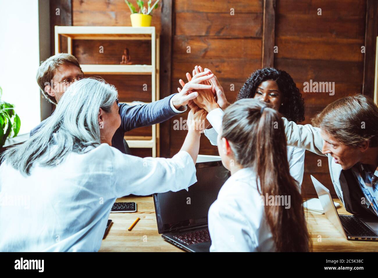 Diverse group joining hands together after successful brainstorming ...