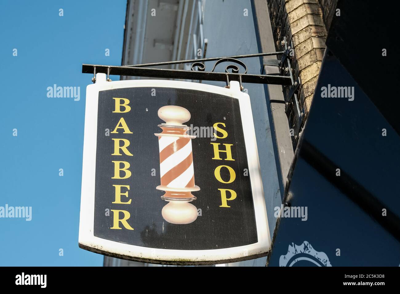 Traditional men's barber pole sign seen attached to the entrance of a ...