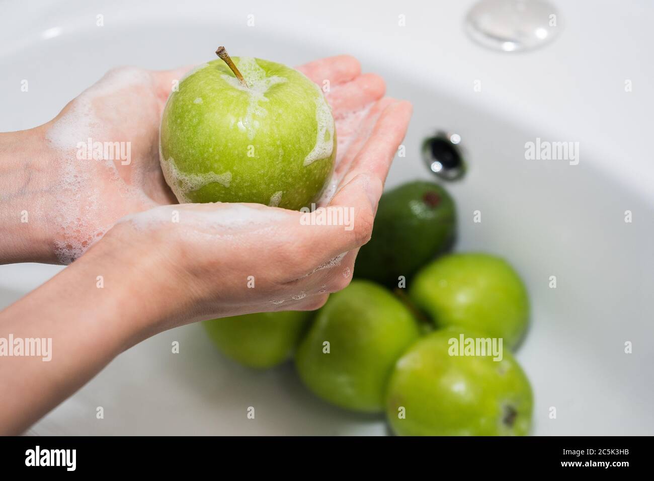Washing fruit. Hands and soapy green apple Stock Photo - Alamy