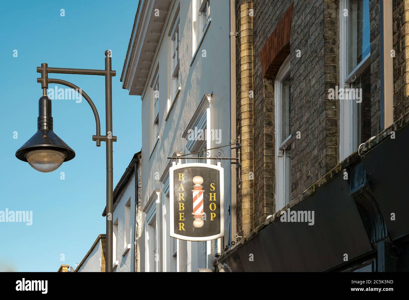 Traditional men's barber pole sign seen attached to the entrance of a ...