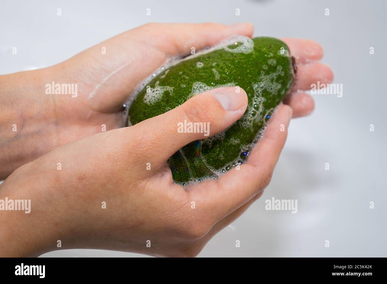 washing fruit with soap and foam. Wash avocados. Hands and soapy green ...