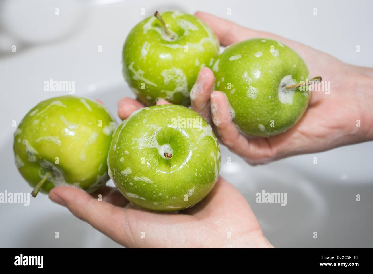 Washing fruit. Girl washes apples. Hands and soapy green apple Stock ...