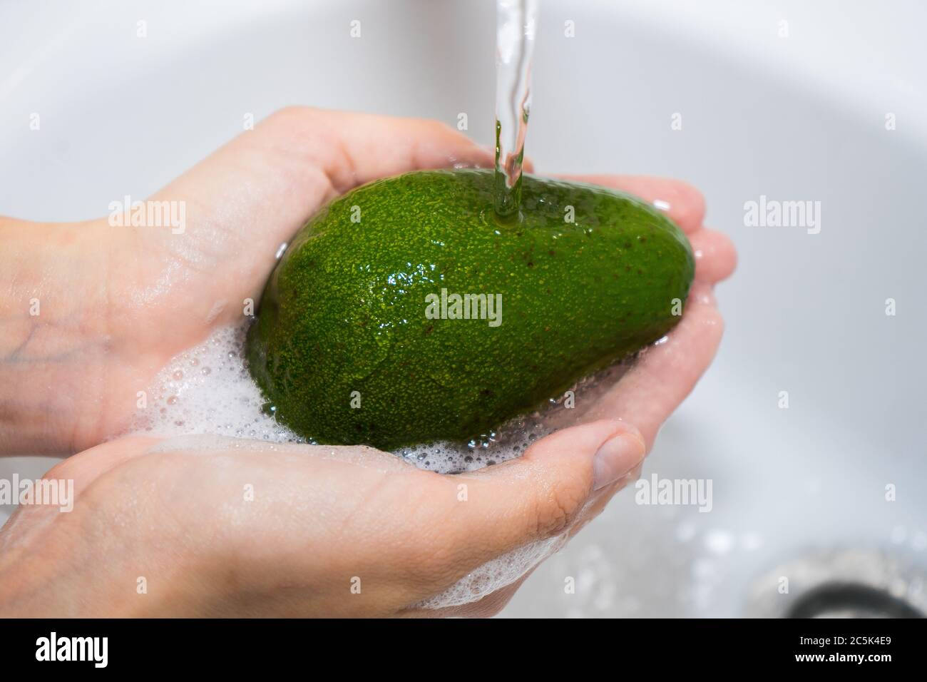 washing fruit with soap and foam. Wash avocados. Hands and soapy green ...