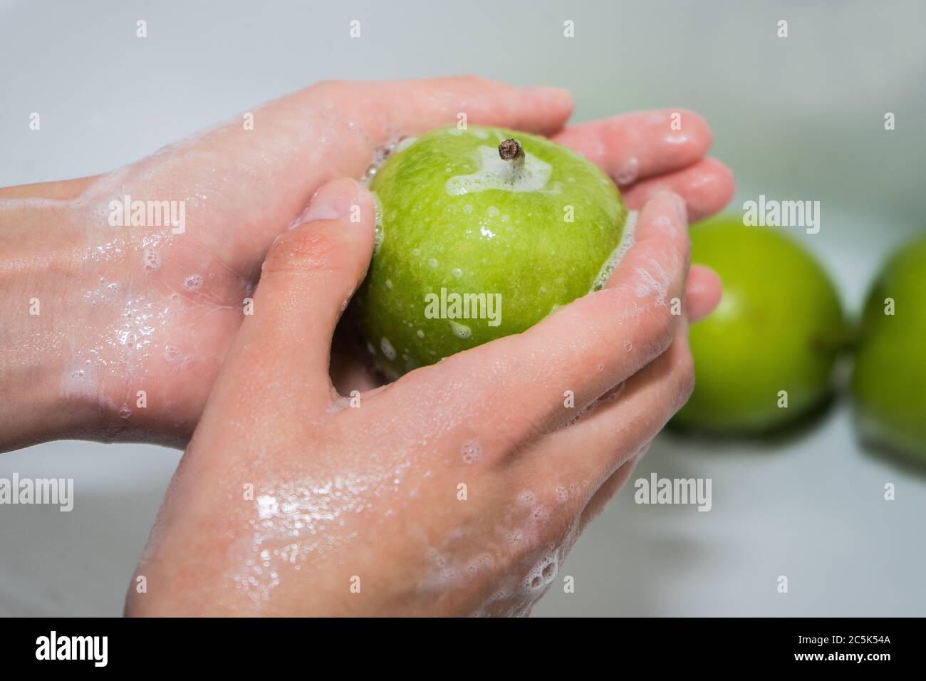Washing fruit. Girl washes apples. Hands and soapy green apple Stock ...