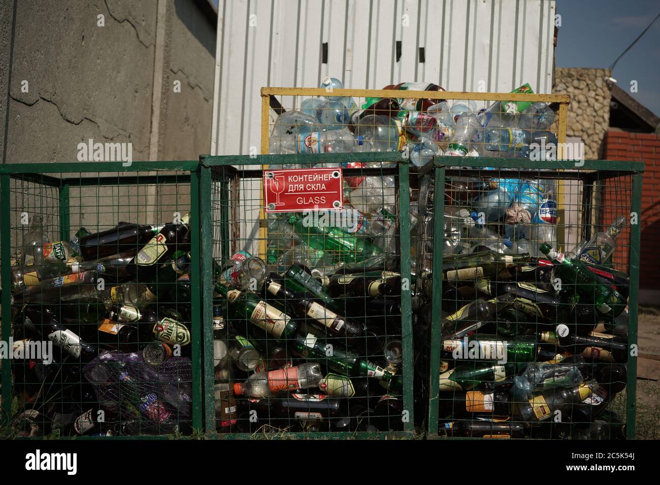Glass bottles in container to glass garbage in foreground. Sorting and ...