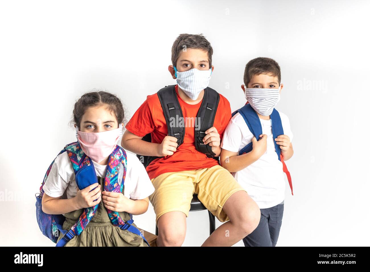 Three kids with backpacks and face masks Stock Photo - Alamy