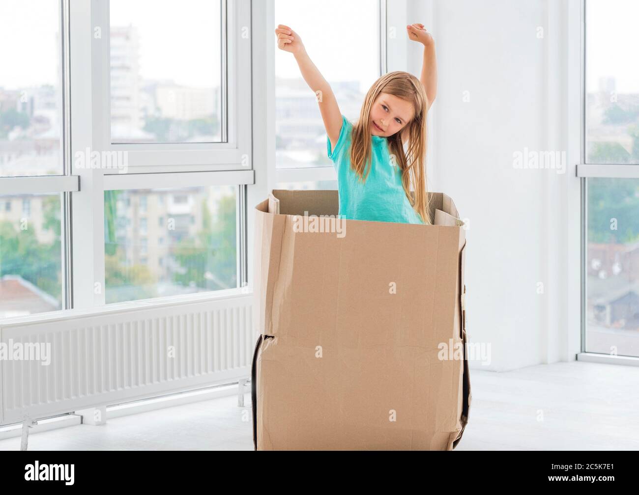 Active playful girl dancing inside brown cardboard box in the room ...
