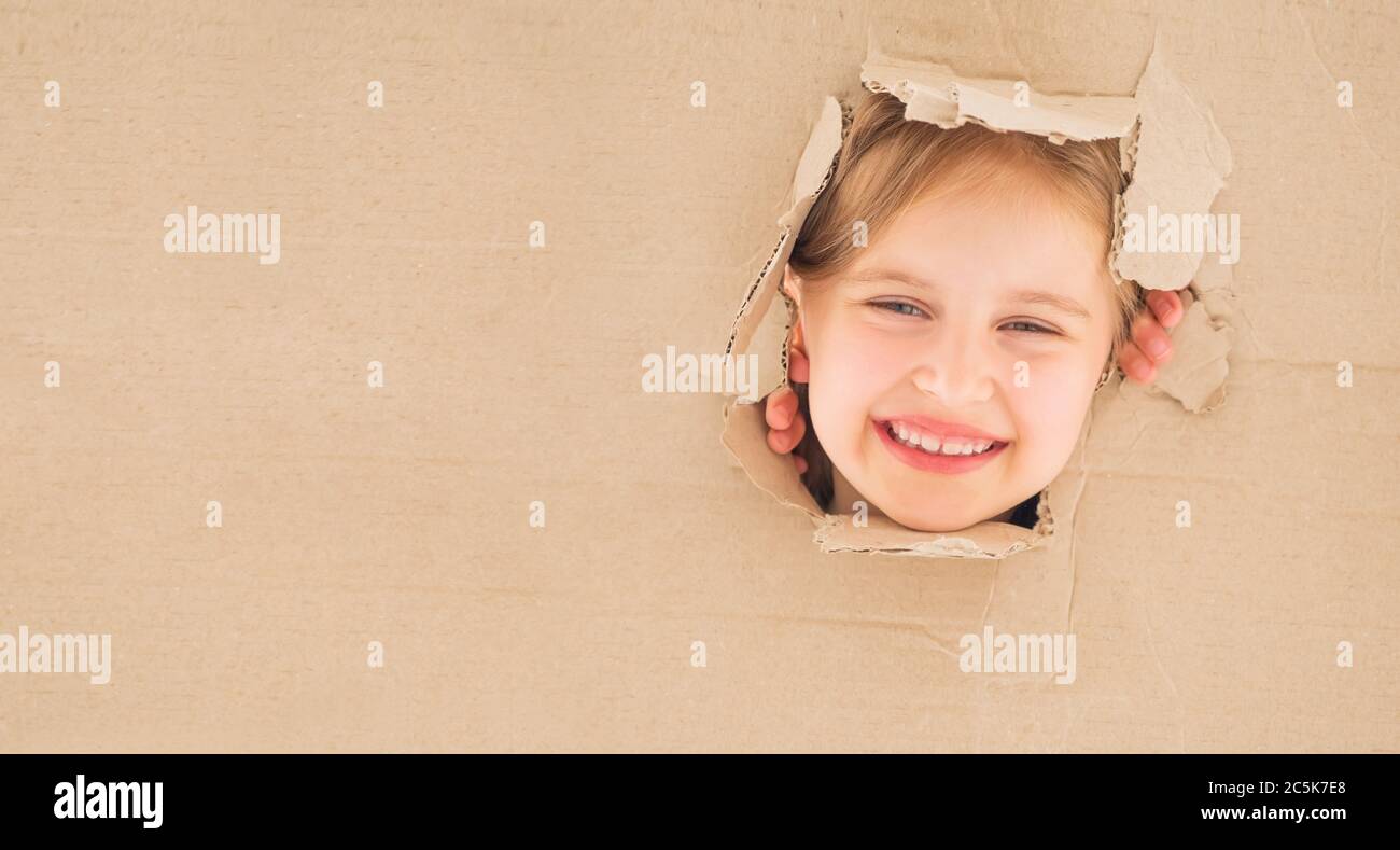 Little girl smiling looking straight from cardboard box Stock Photo - Alamy
