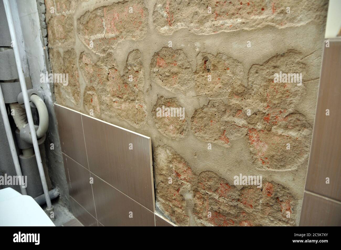 Wall of the toilet room with fallen off tiles, the defect of decoration ...