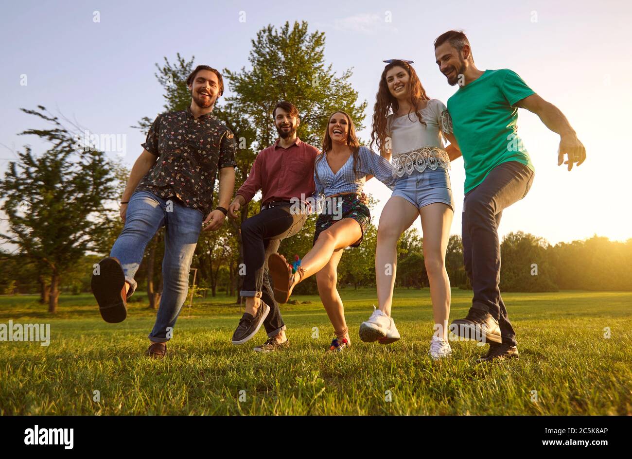 Happy friends dancing and laughing outdoors at sunset. Joyful young ...