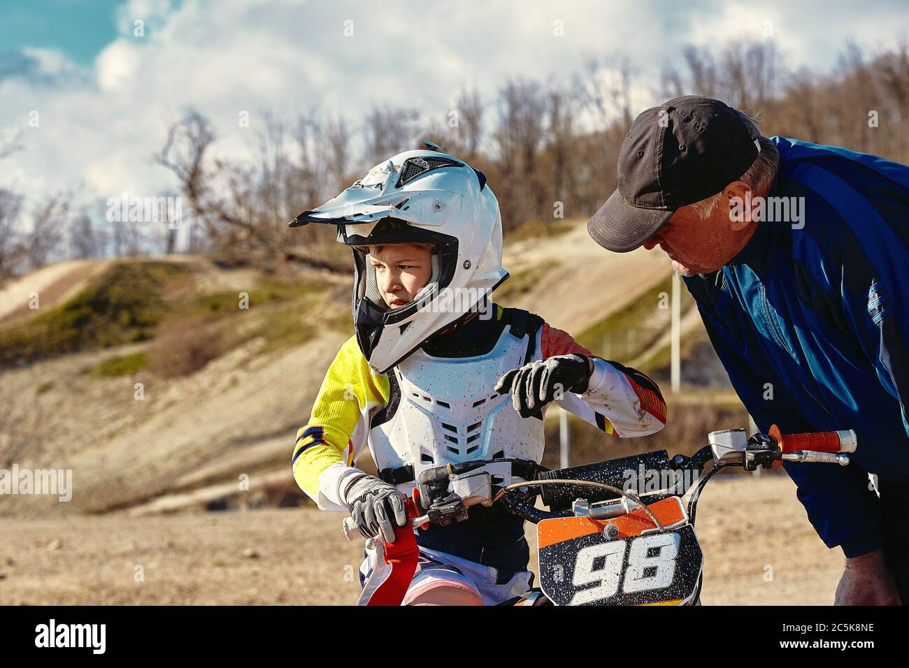 kids riding at motobike, junior competition on motorcycle. Coach gives ...