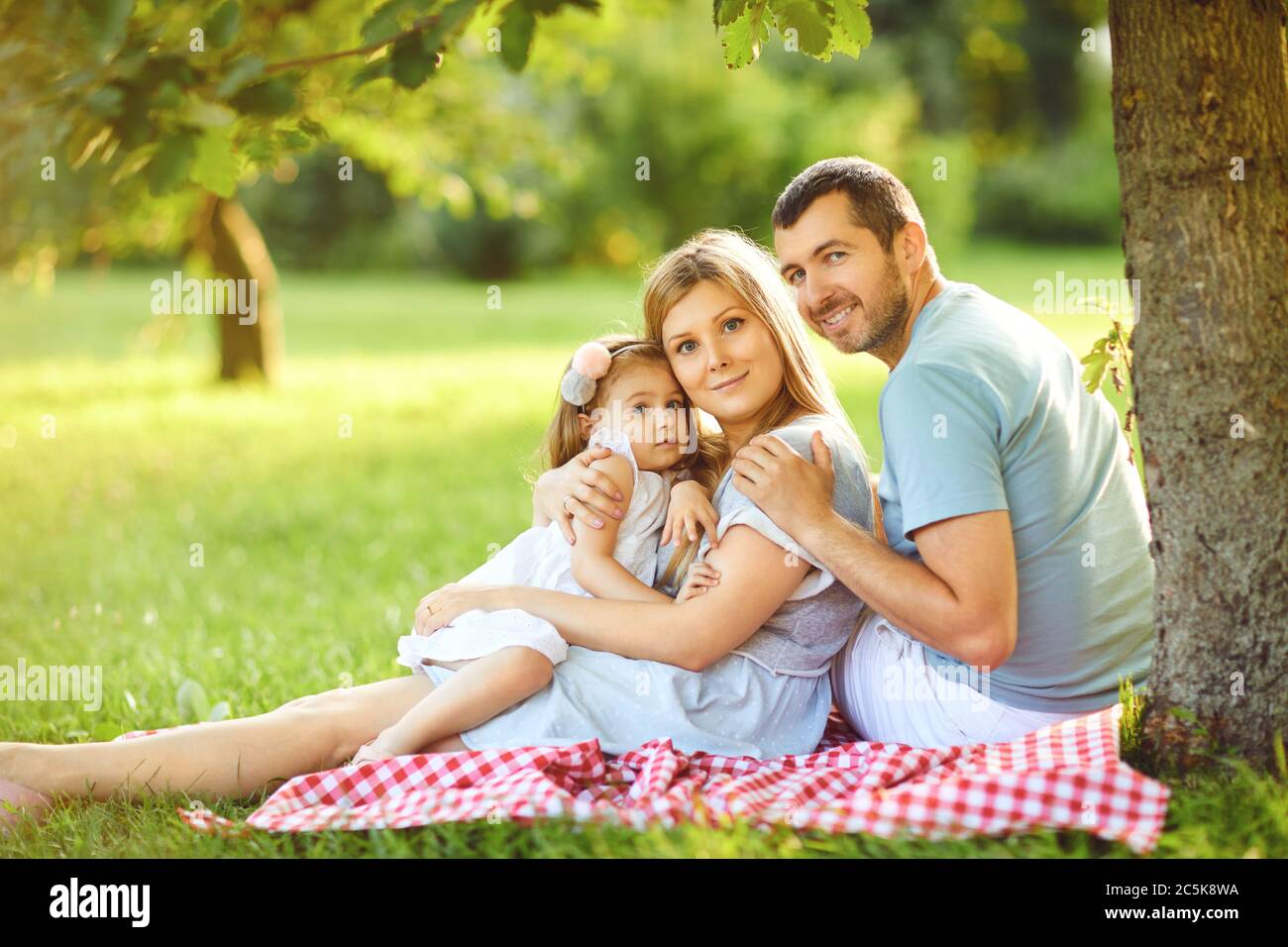 Happy family is hugging while sitting in the park Stock Photo - Alamy