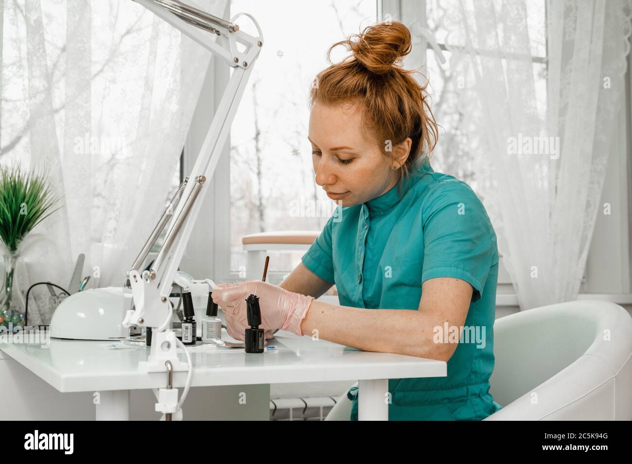 Manicurist at work in the office. Drawing gel polish on tips, creating ...