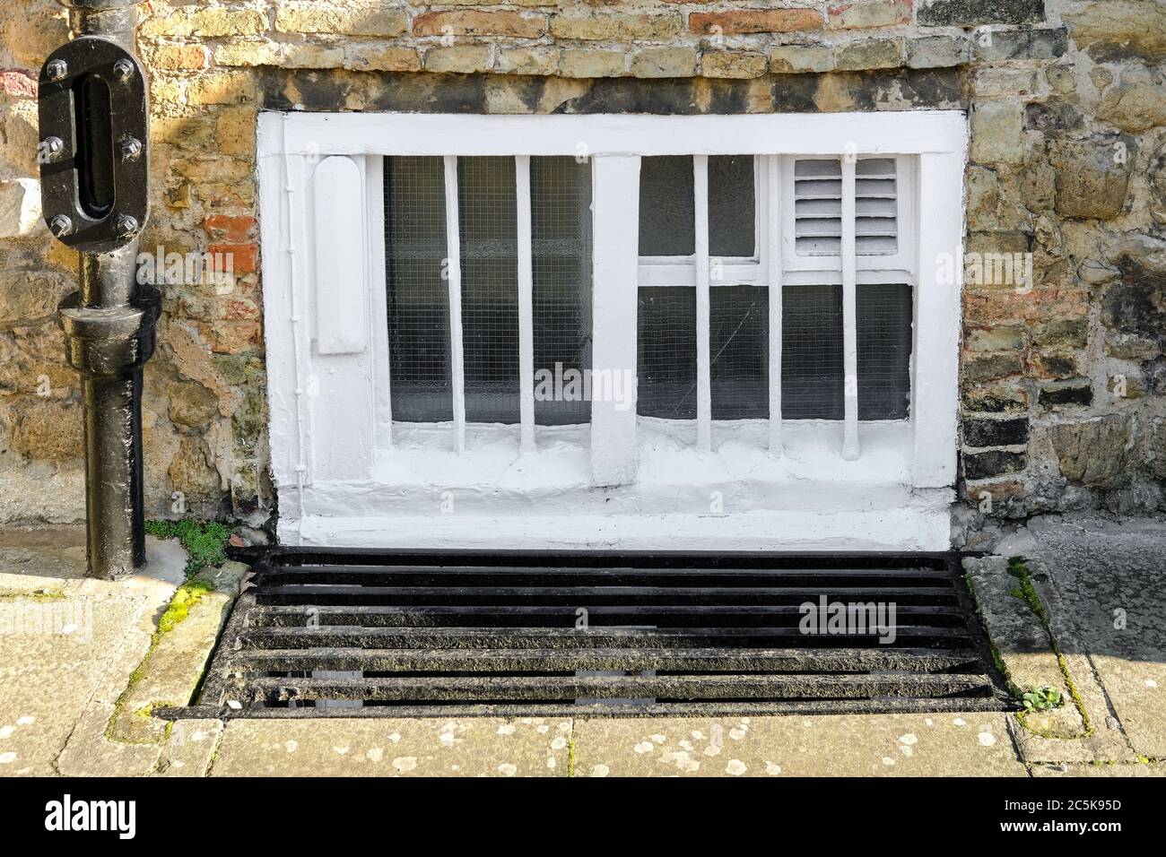 Newly painted basement window seen from the adjacent pavement. A metal ...